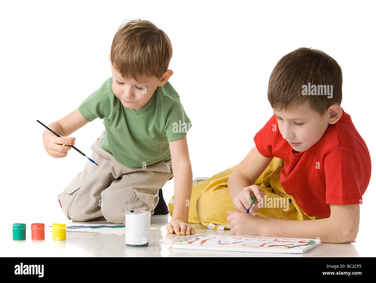 two boys draw with paints sitting on floor isolated on white Stock ...