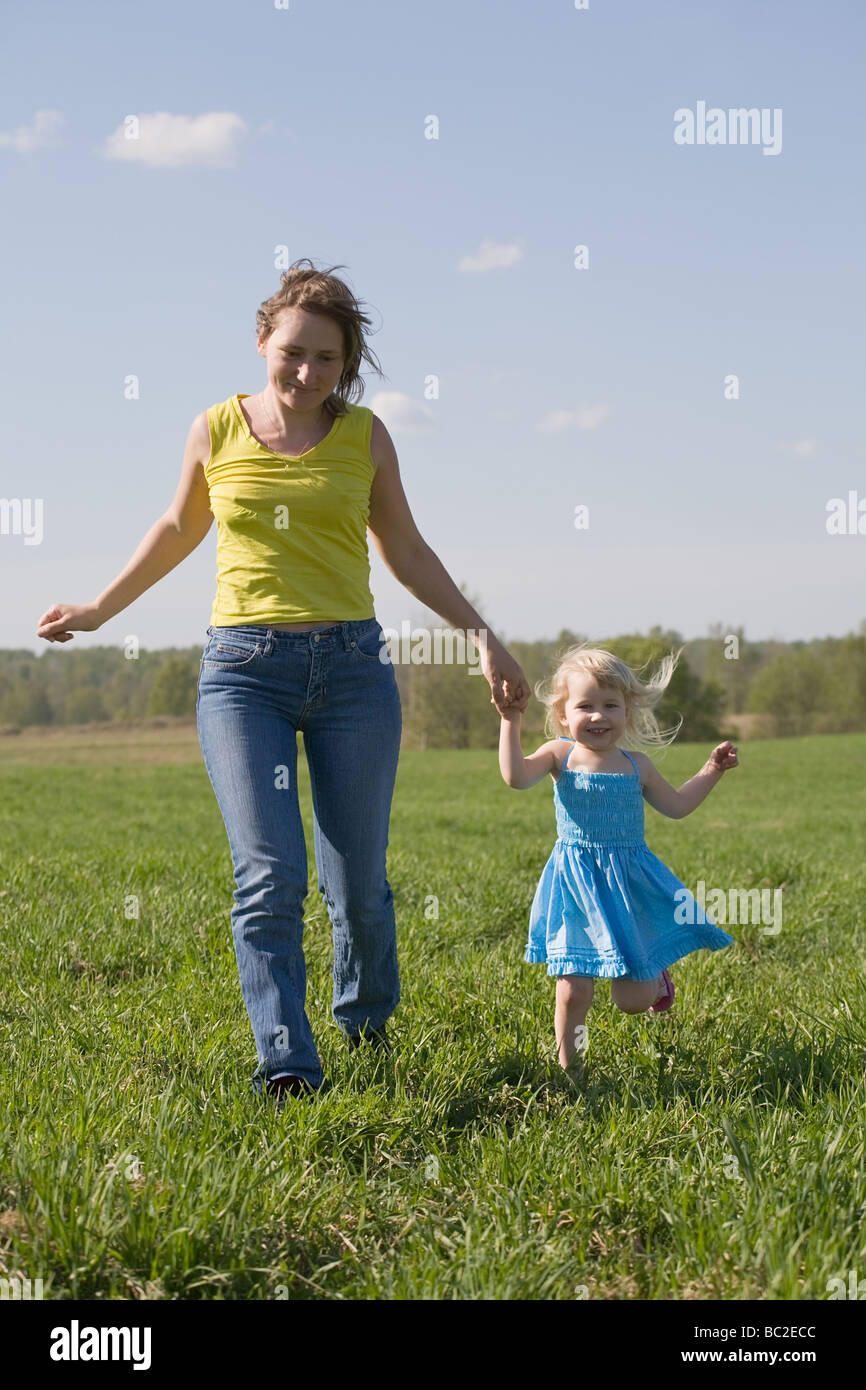 happy mother running with her little daughter across green summer ...