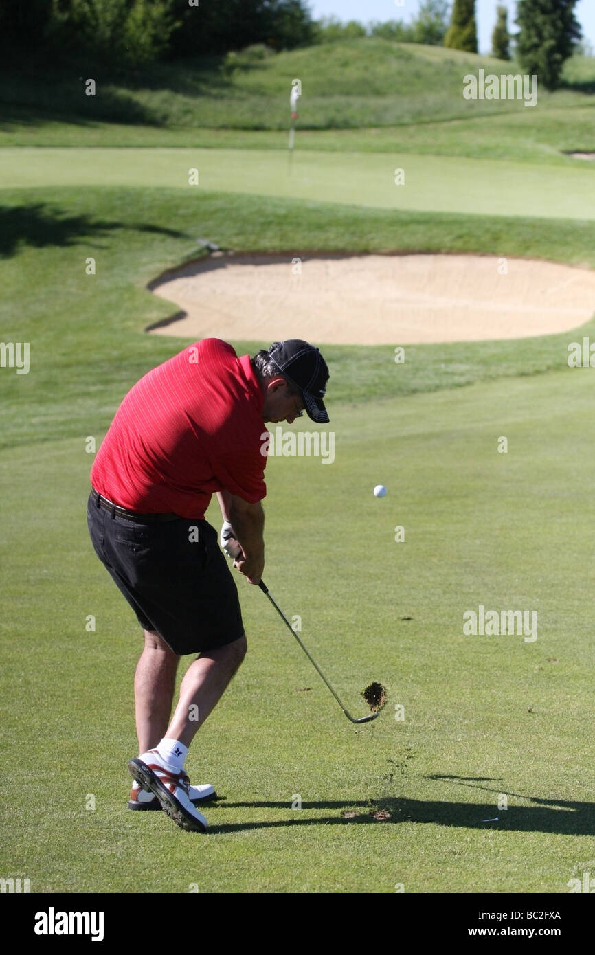 A golfer with a great swing takes a perfect divot while hitting an ...