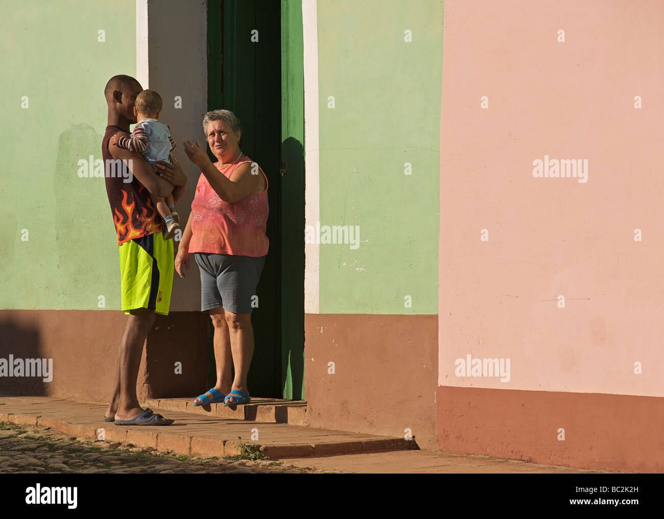 Cuban father with young child greets a neighbour. The houses in ...