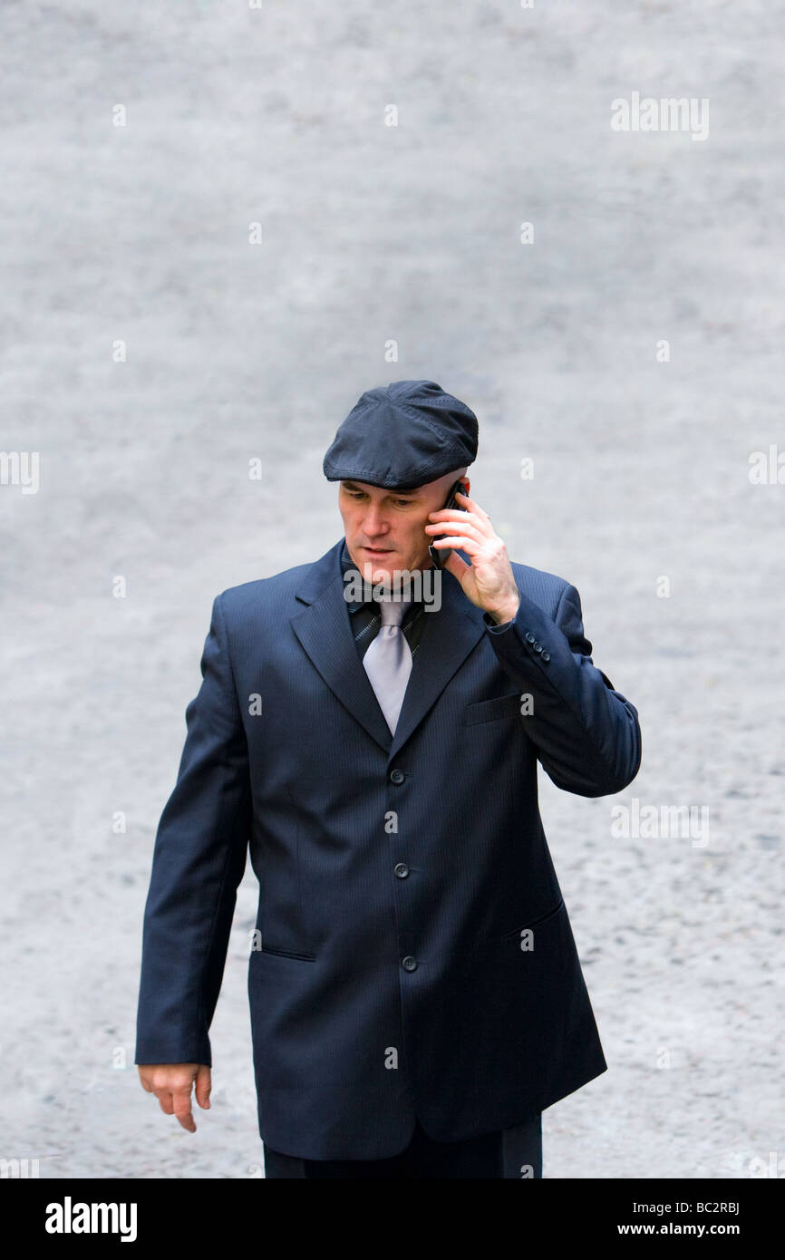 Bald man in his late 40's wearing a dark suit and cap speaking on a ...