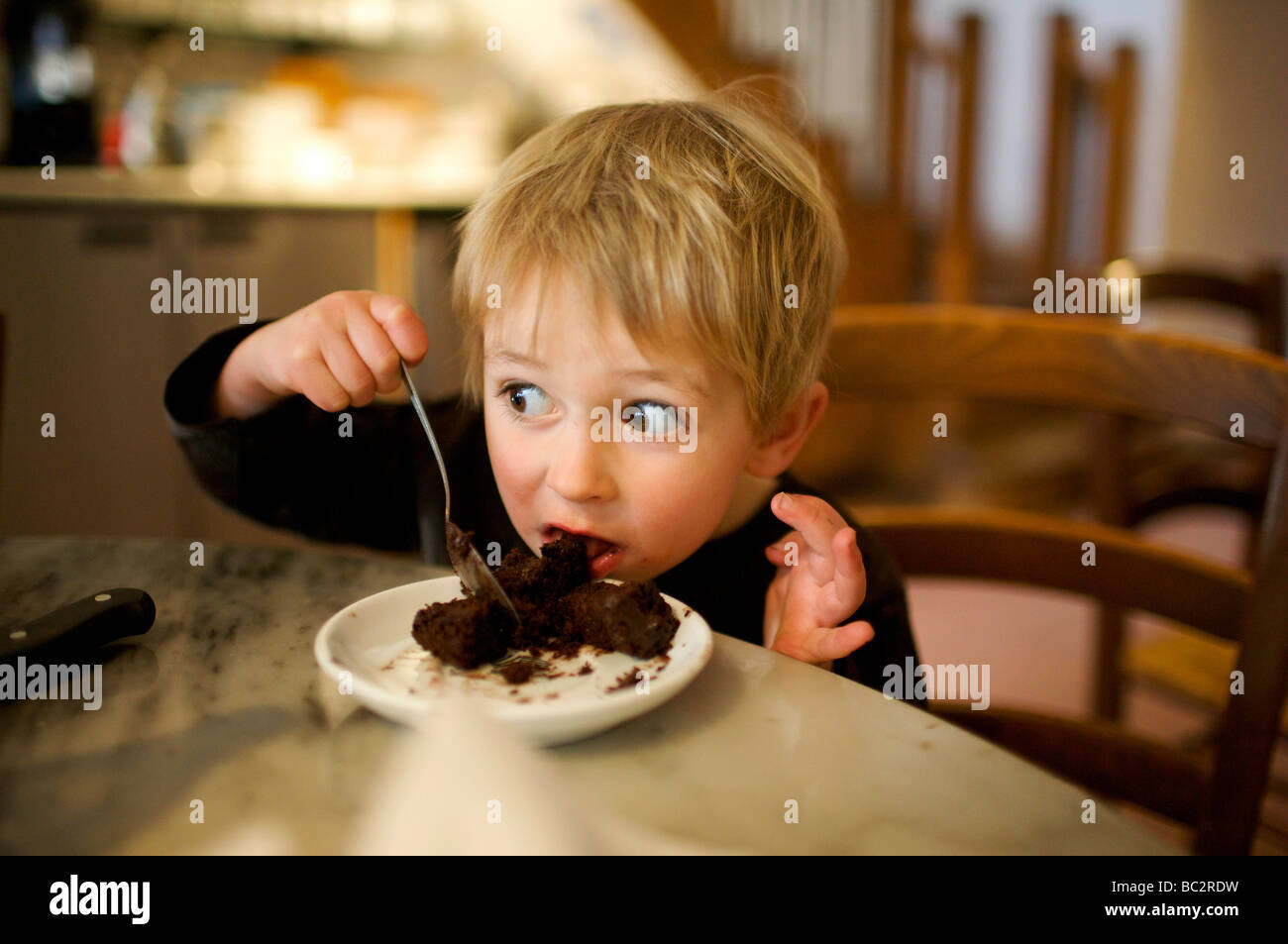 Young boy eating chocolate cake in a restaurant Stock Photo - Alamy