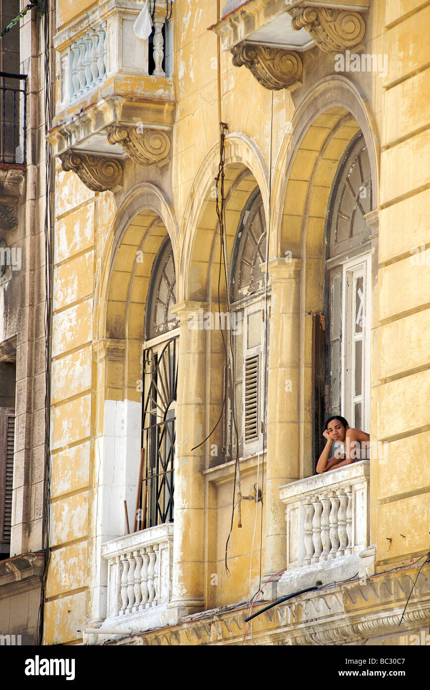 Cuban woman peering from the window balcony of a colonial building in ...