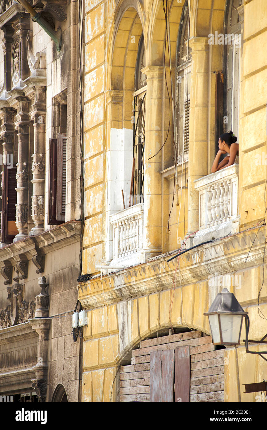 Cuban woman peering from the window balcony of a colonial building in ...