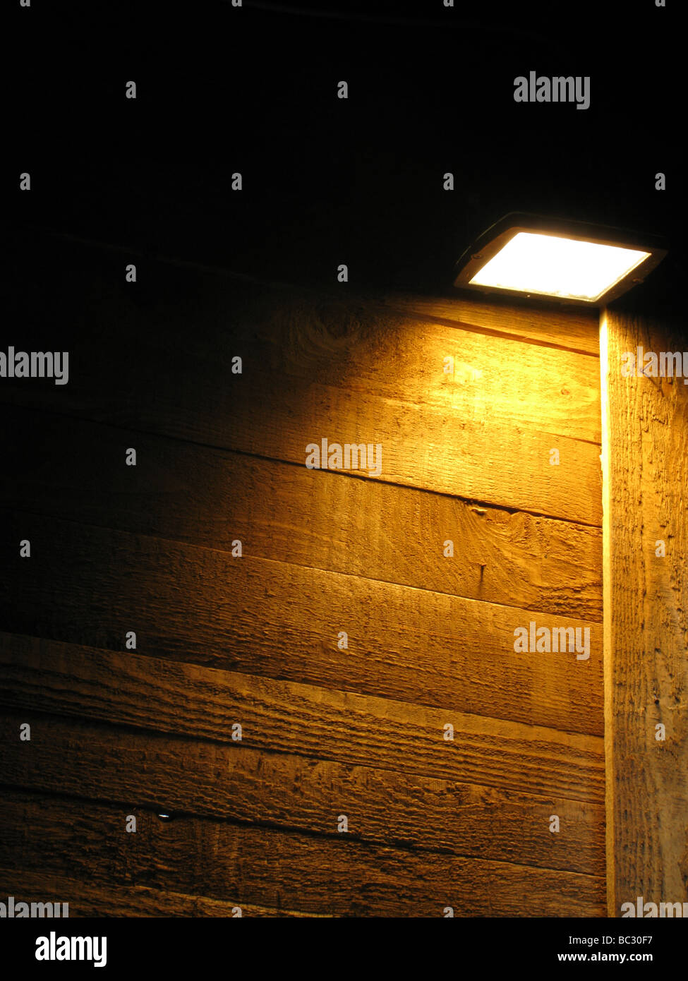 one bright spot light and high wooden wall at night Stock Photo - Alamy