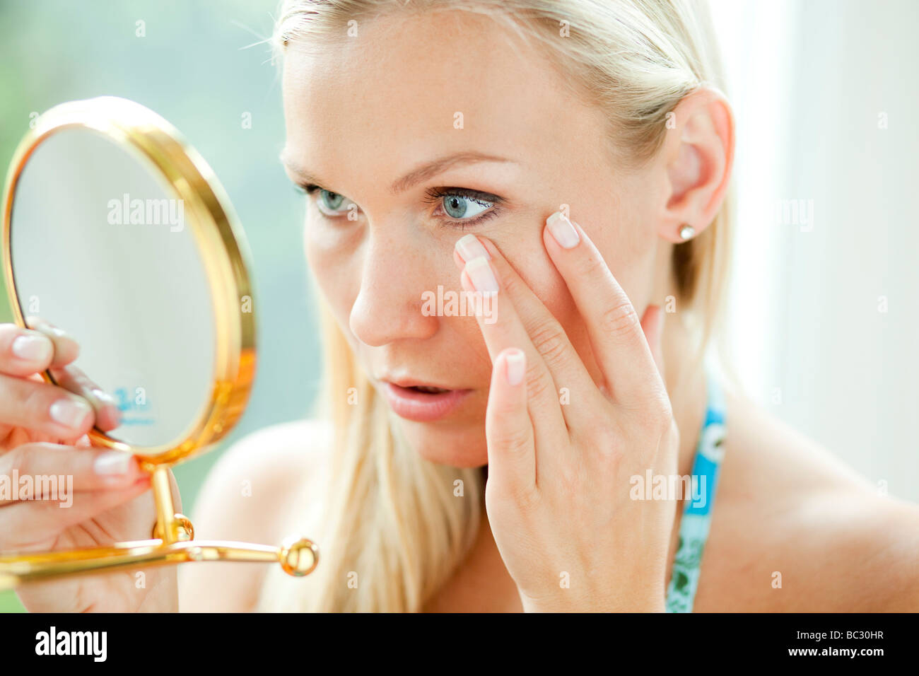 Woman looking in mirror Stock Photo - Alamy