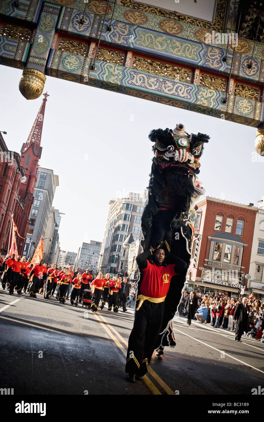 A pair of lion dancers marches on the parade route backed by their ...