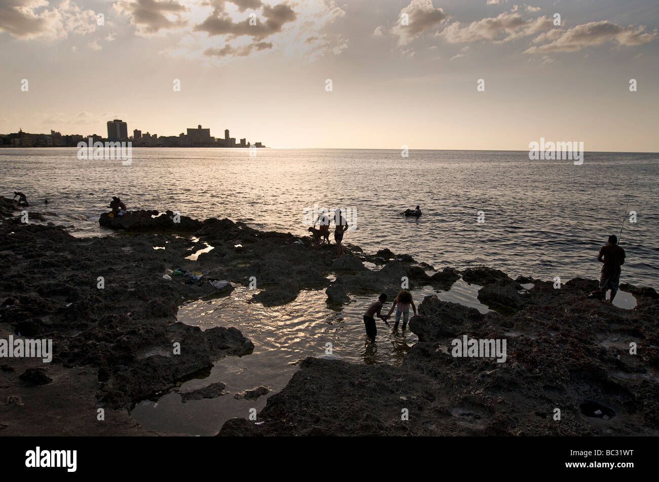 Cubans enjoying the sun and sea off the rocks alongside the Malecon at ...
