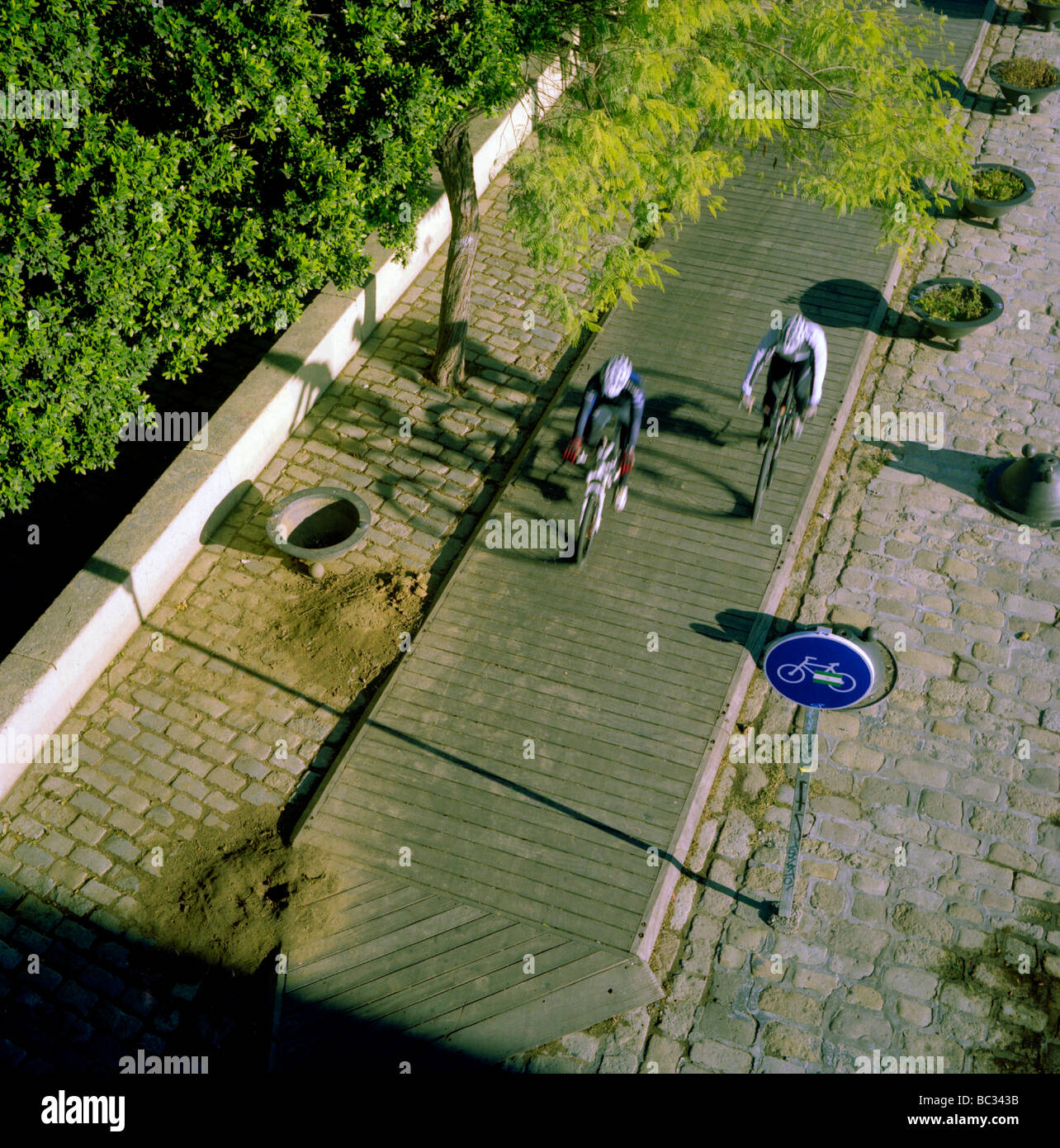 Cyclists seen from above riding along the riverside path in Seville ...