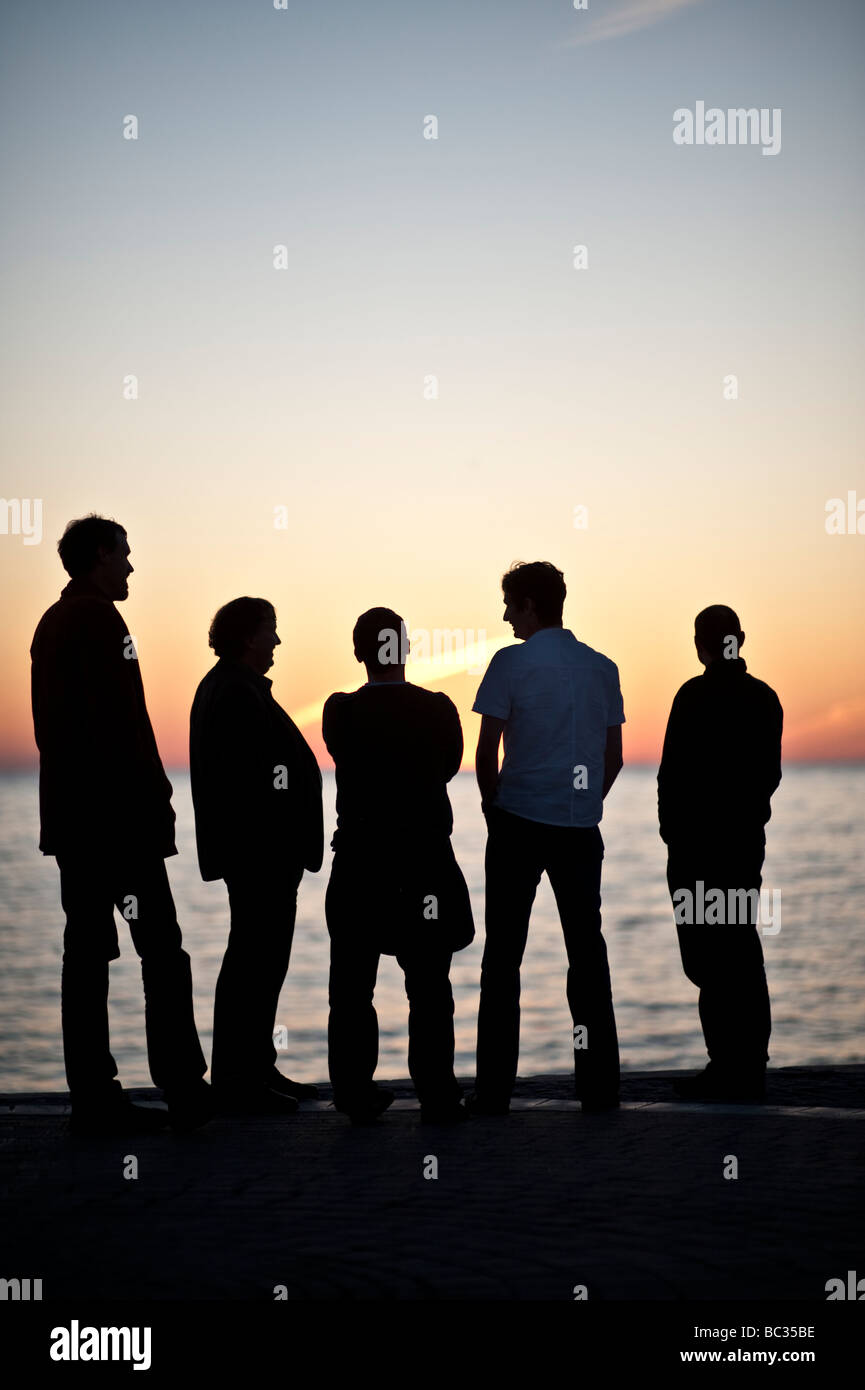 Silhouette of five men standing watching the sunset over Cardigan Bay ...