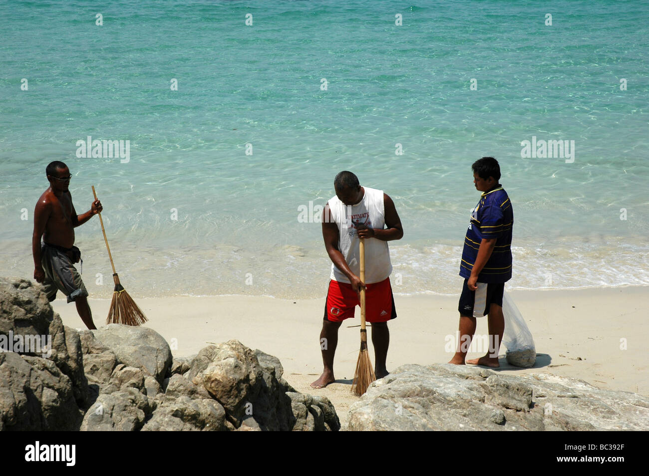 Phuket.Beach cleaners sweep the beach Stock Photo - Alamy