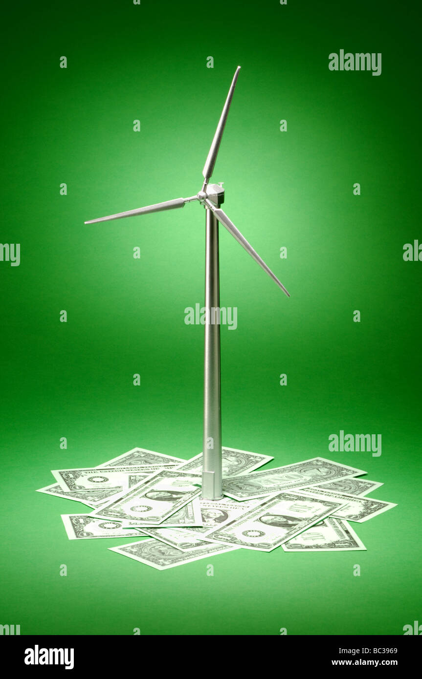 A small metal wind turbine on a green background dollar bills money ...