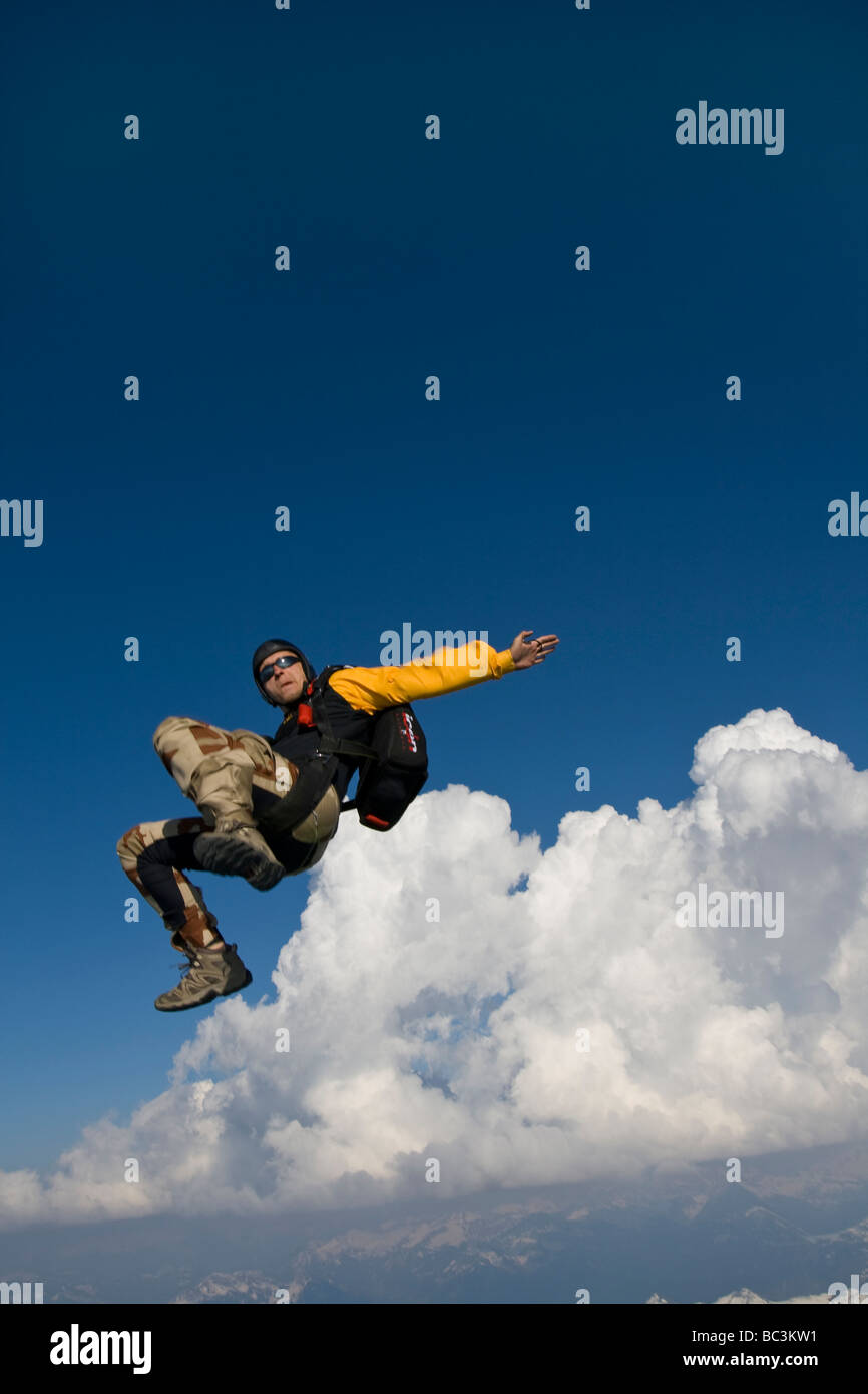 Skydiver is sit flying in between clouds and having a blast. He tries ...