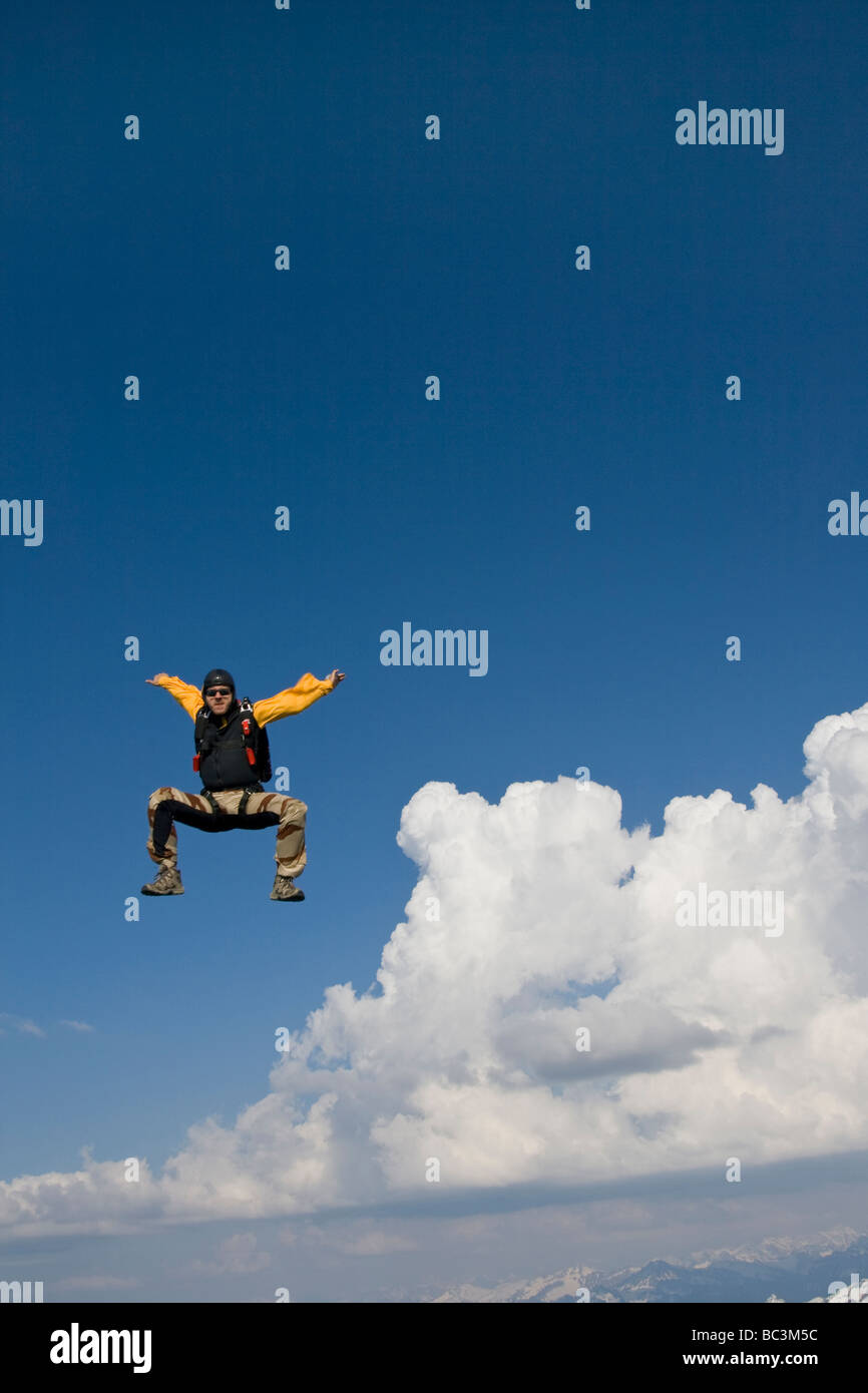 Skydiver is sit flying in between clouds and having a blast. He tries ...