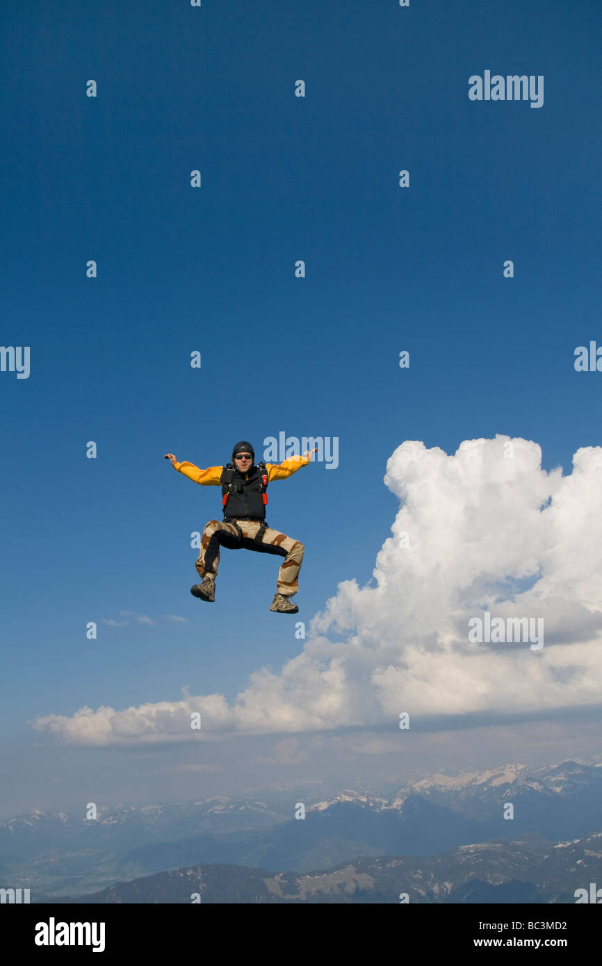 Skydiver is sit flying in between clouds and having a blast. He tries ...