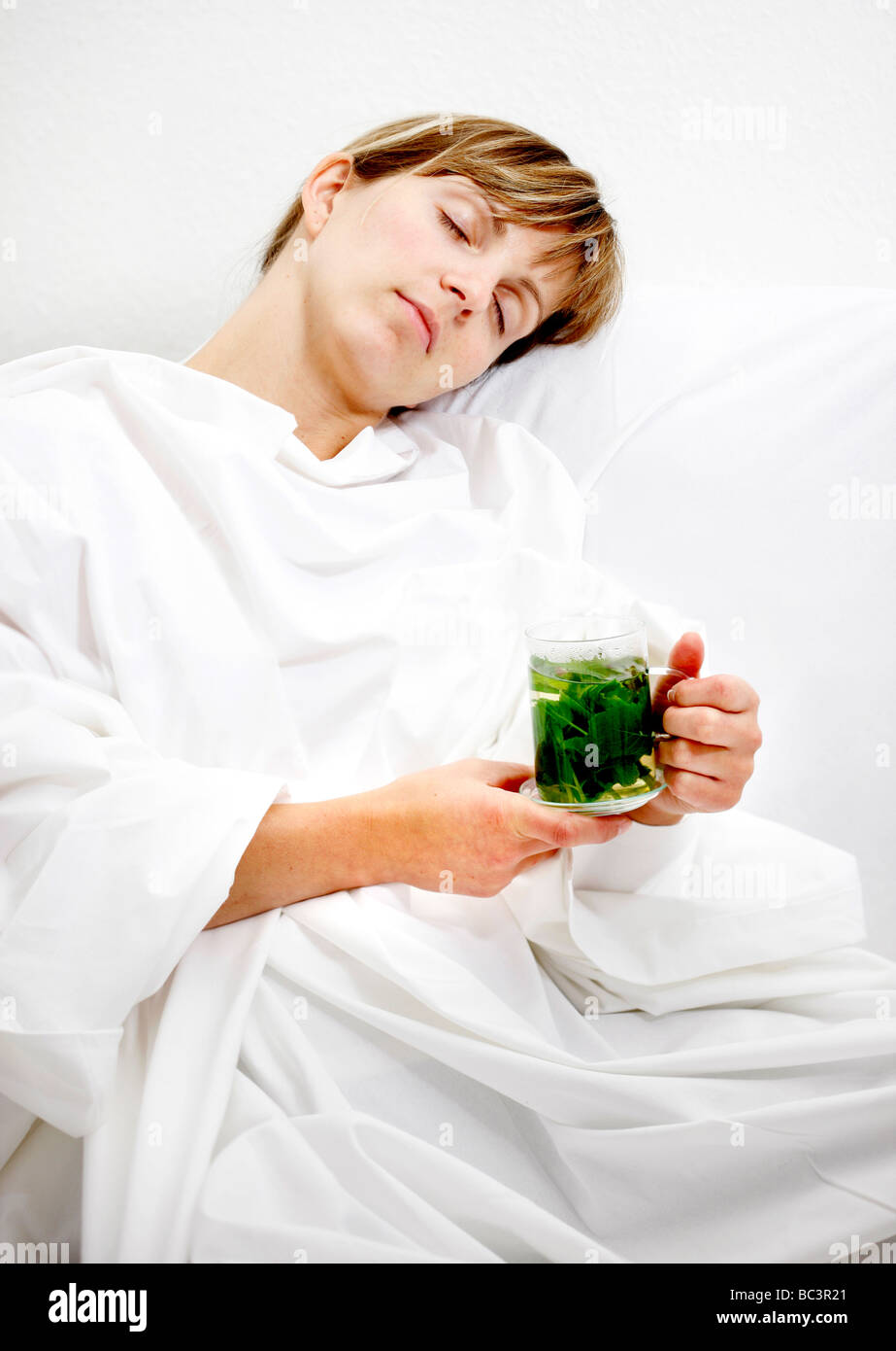 Woman in bed has a cold a sore throat Drinks a hot peppermint tea made ...