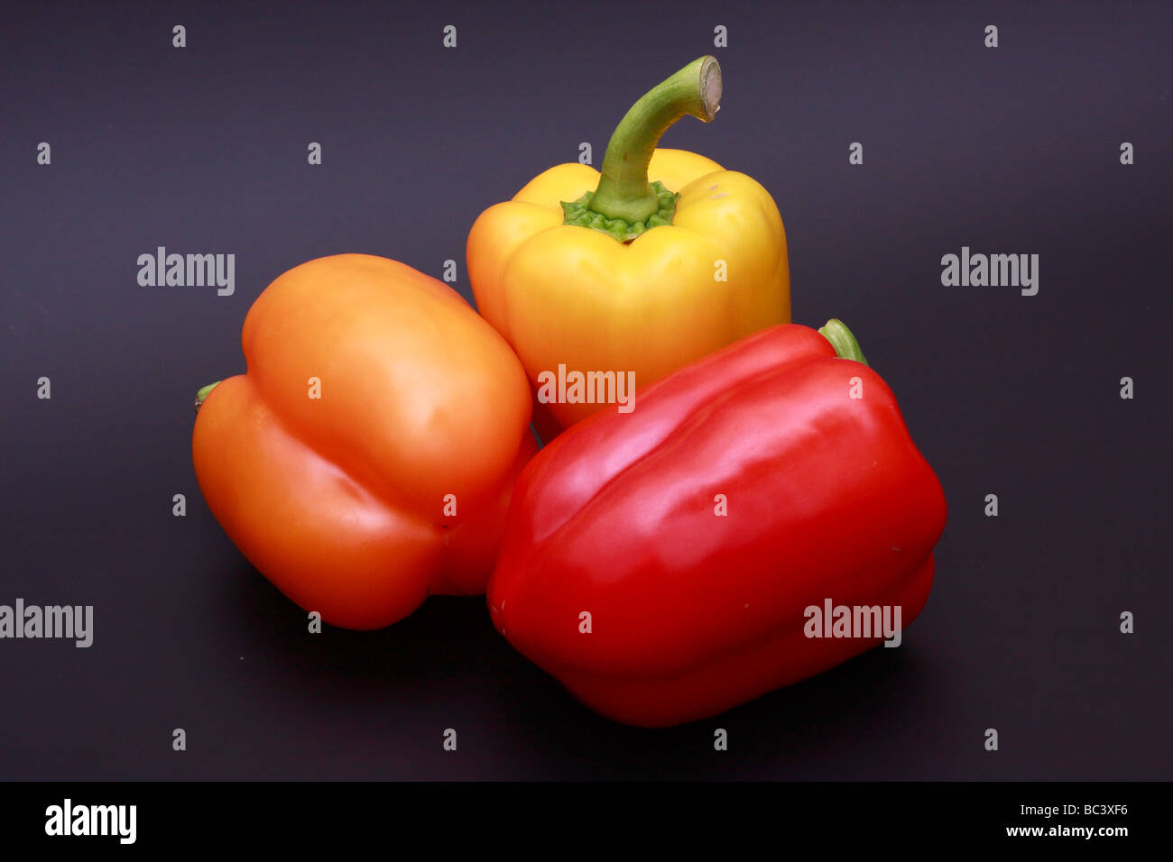 three peppers over dark grey background Stock Photo - Alamy