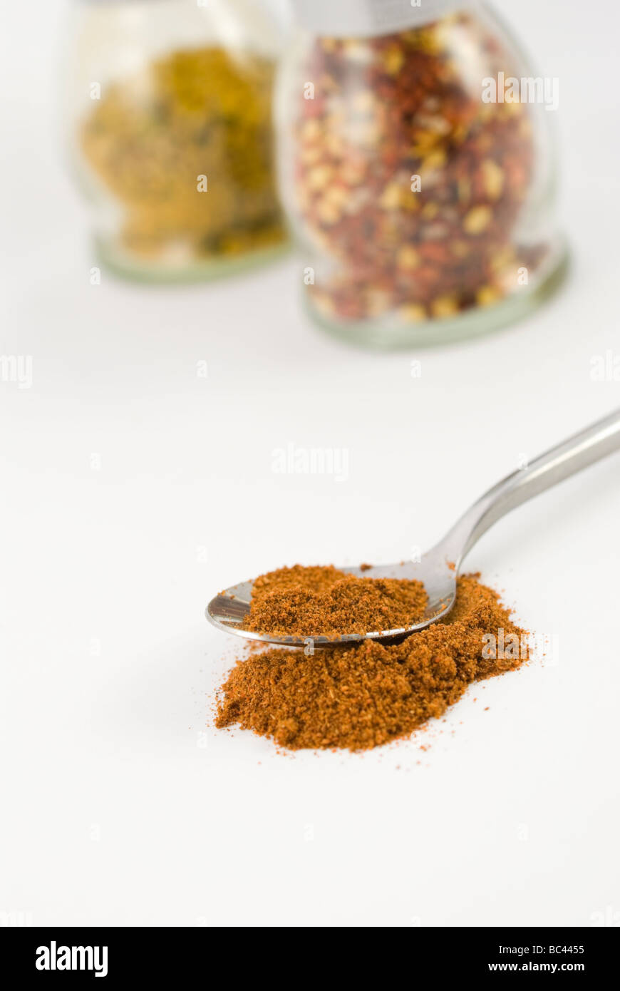 Chili pepper powder arranged on white background with silver spoon and ...