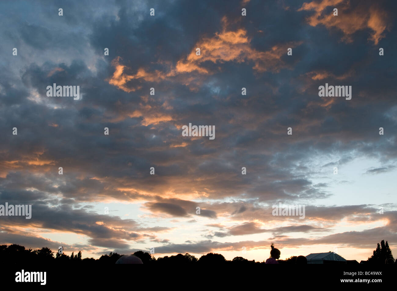 Sunset with clouds under lit by setting sun against dark foreboding ...