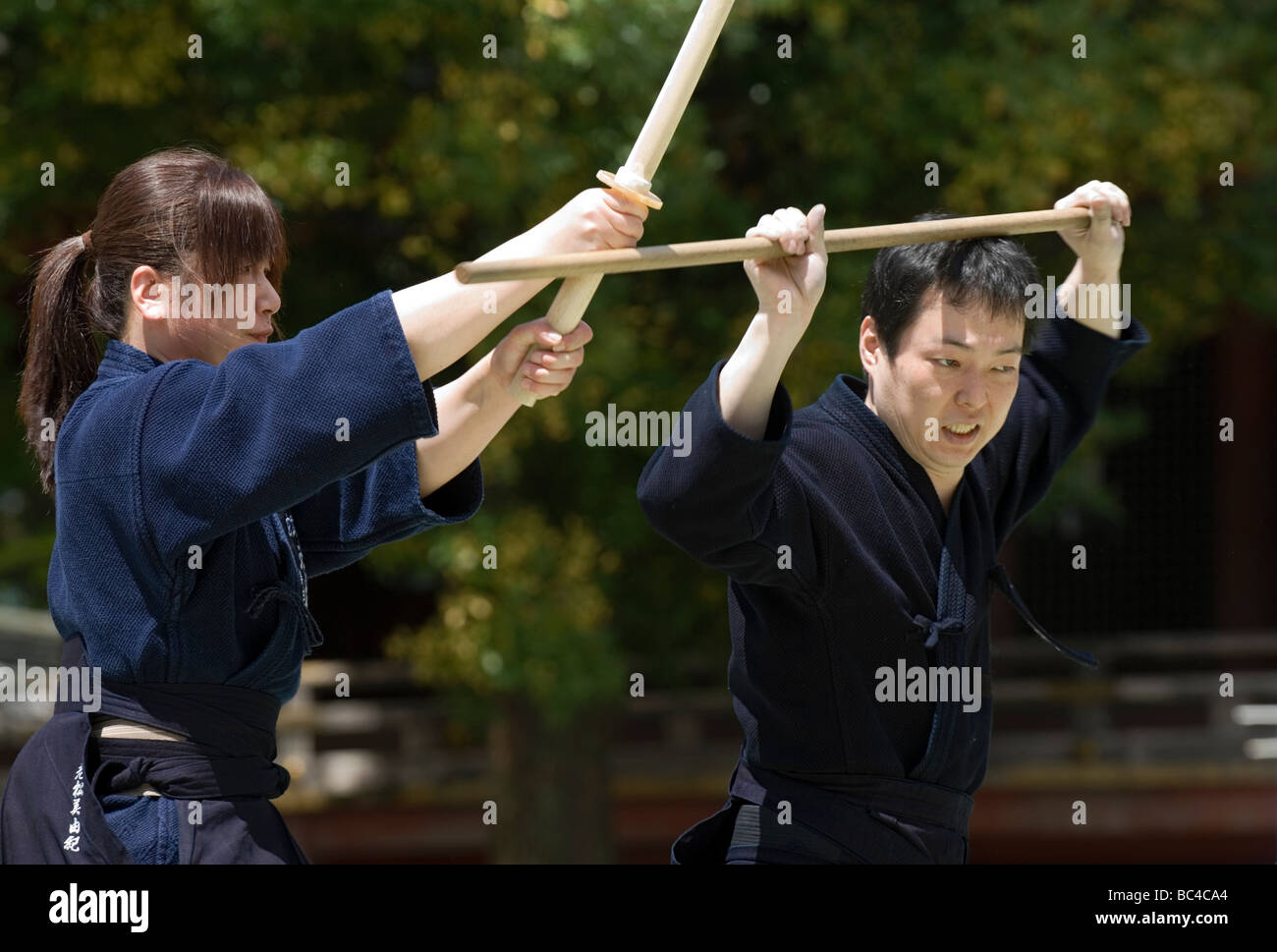Two People Sparring With Wooden Sticks In A Swordsmanship Training Exercise Called Kenjutsu