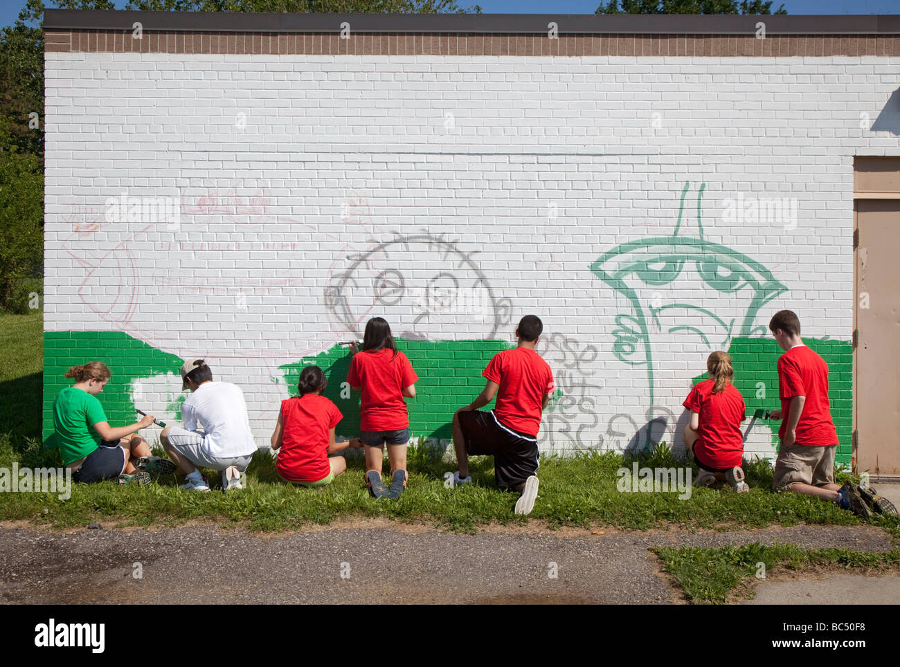 Youth volunteers paint wall in city park Stock Photo - Alamy