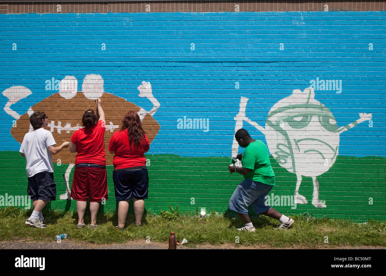 Youth volunteers paint wall in city park Stock Photo - Alamy