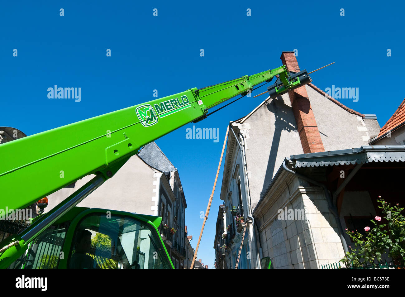 Building contractor in bucket of extending jib crane repairing house ...