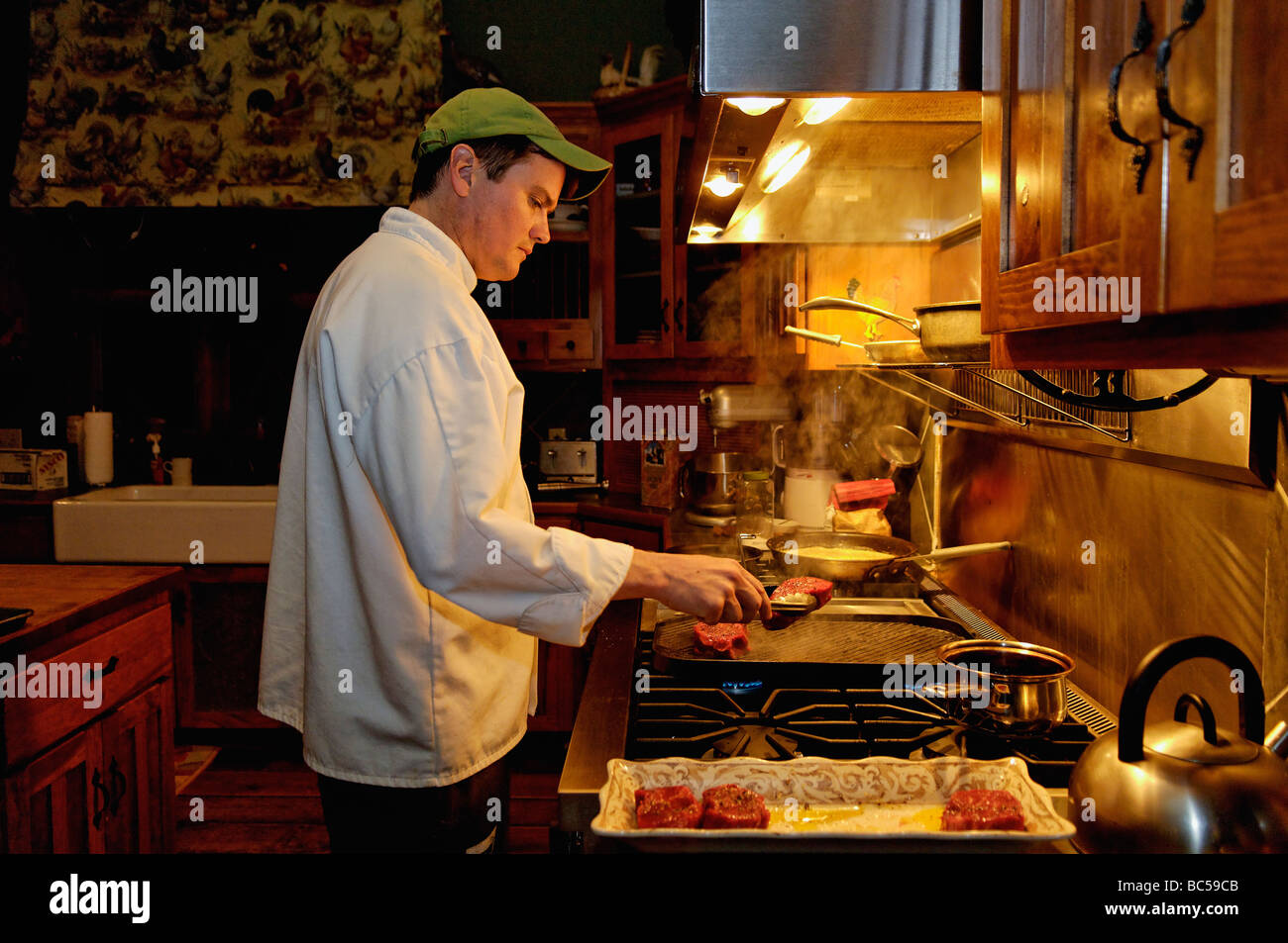 Chef Preparing Steaks in Kitchen with Commercial Stove Stock Photo - Alamy