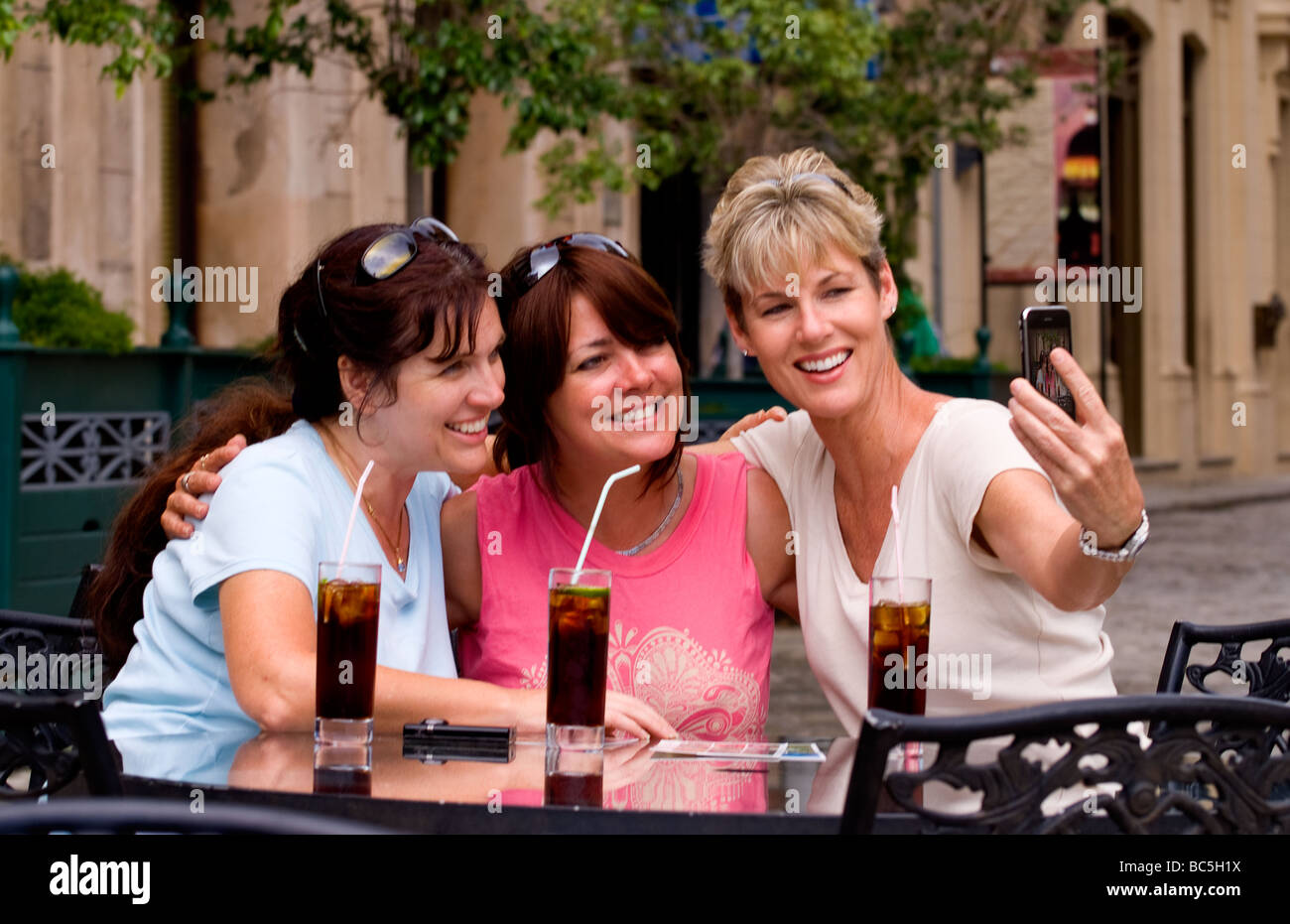 Tourist girl friends relax with drinks and take Iphone photos and have ...