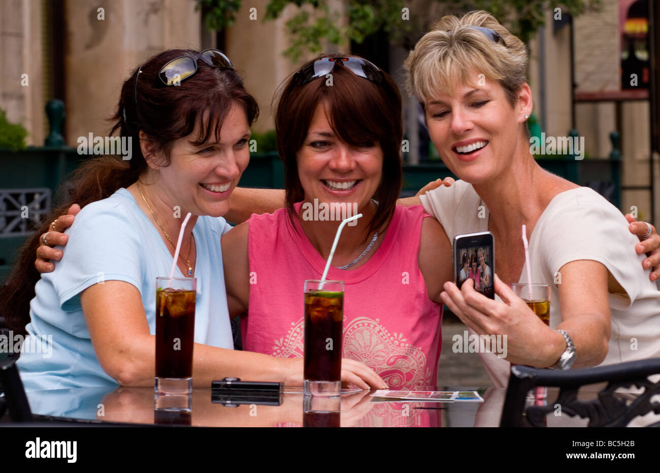 Tourist girl friends relax with drinks and take Iphone photos and have ...