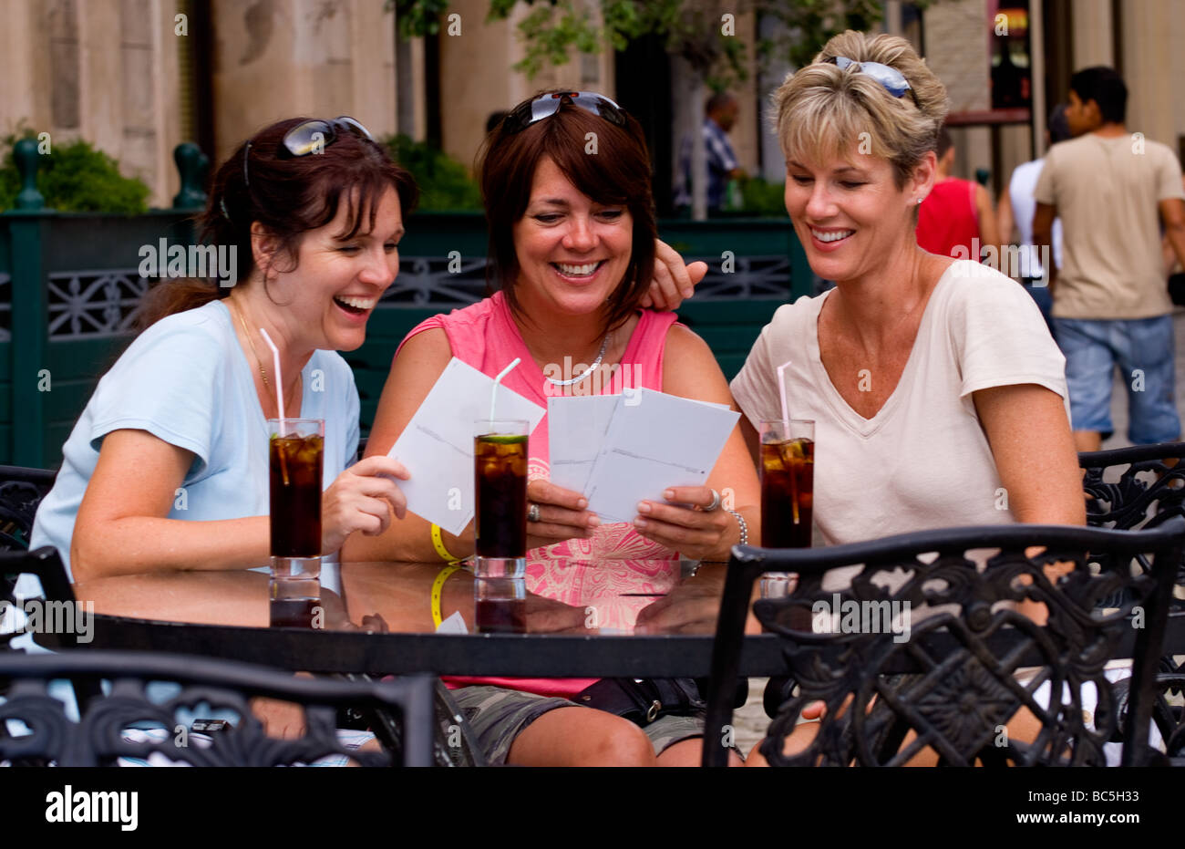 Tourist girl friends relax with drinks and look at postcards and have ...