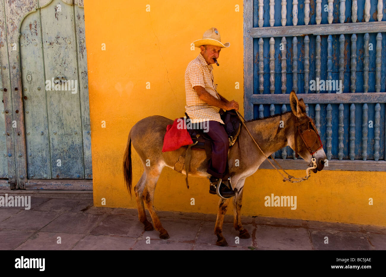 Old man riding donkey for tourists in the old colonial city of Trinidad ...