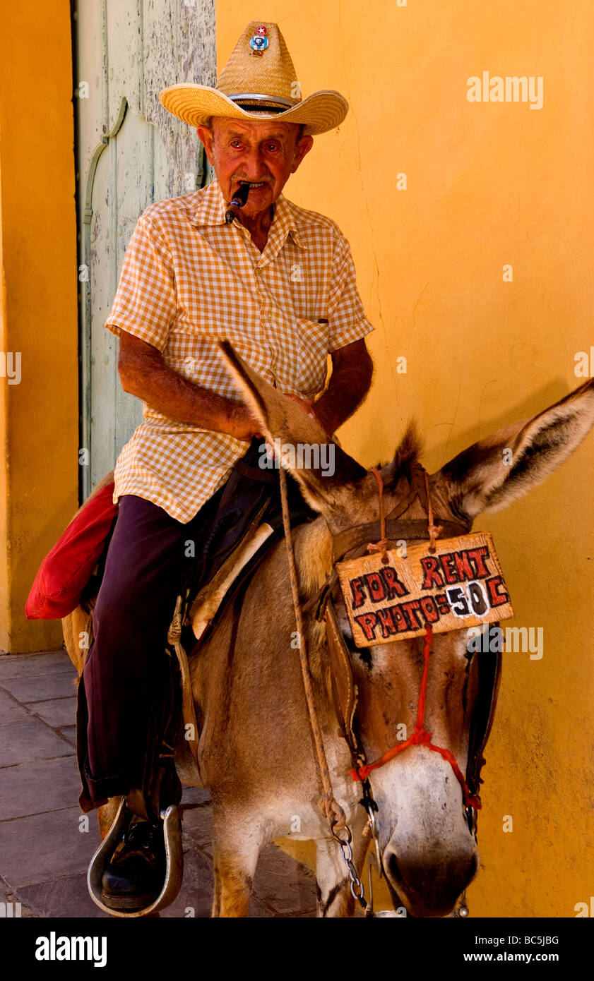 Old man riding donkey for tourists in the old colonial city of Trinidad ...