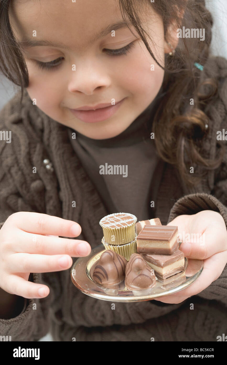 Girl taking a chocolate from a small tray of chocolates Stock Photo - Alamy