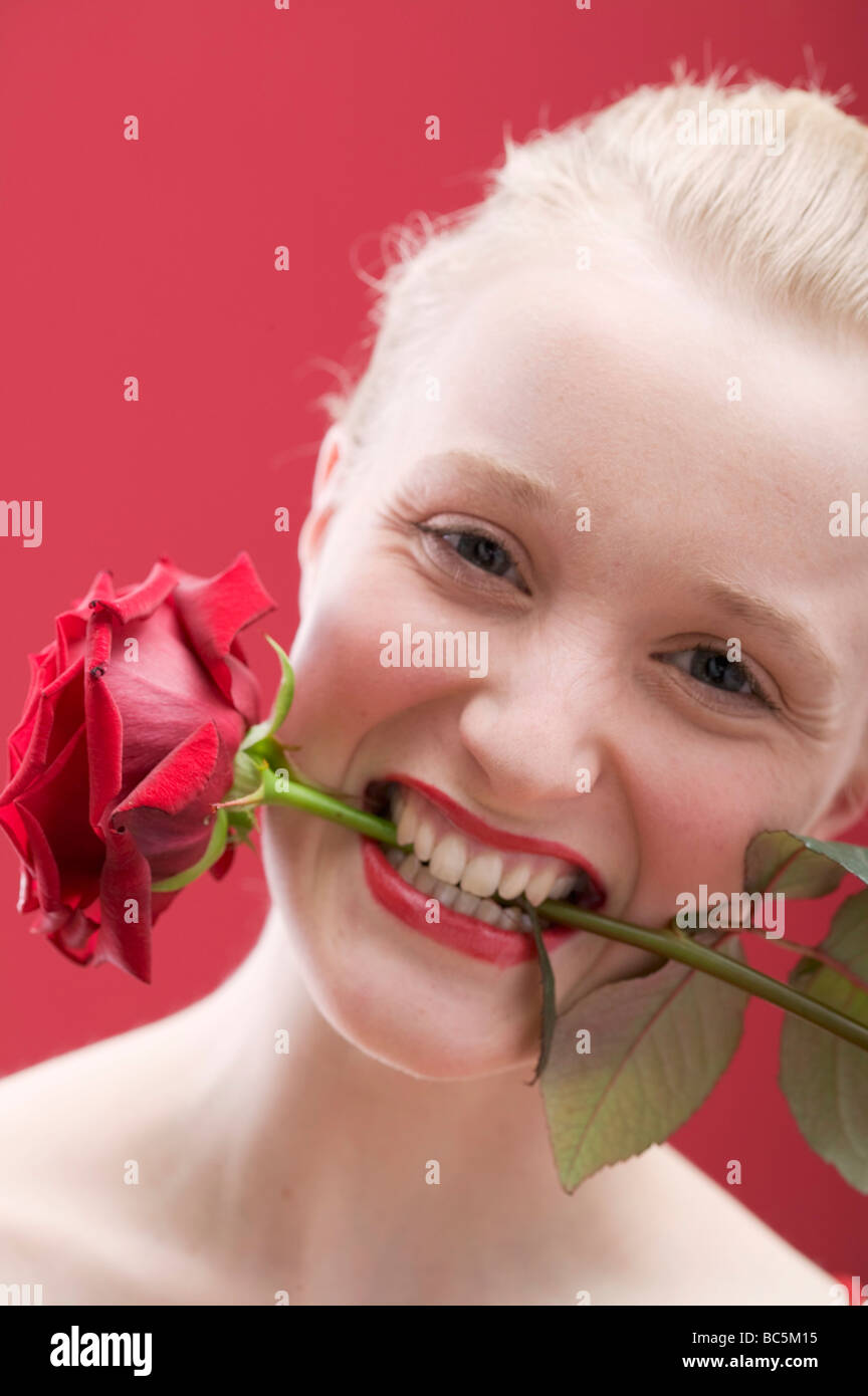 Young woman with a red rose in her mouth Stock Photo - Alamy