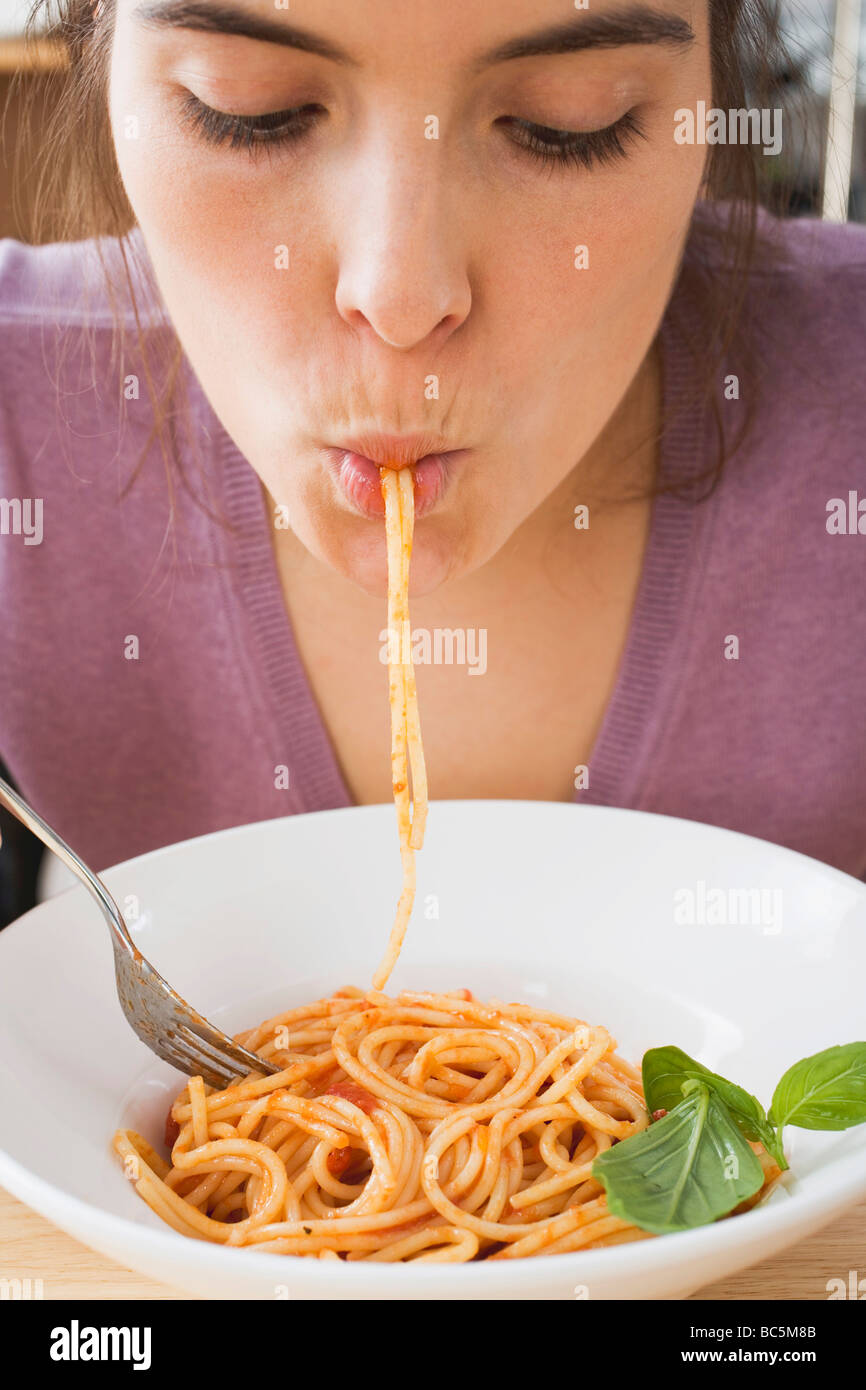 Young woman eating spaghetti with tomato sauce Stock Photo - Alamy