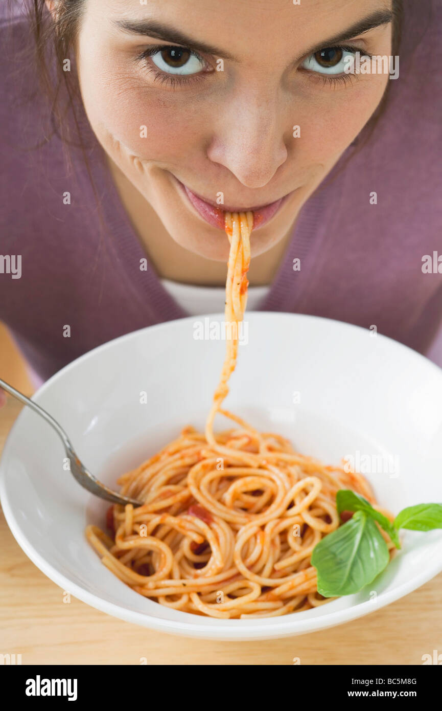 Young woman eating spaghetti with tomato sauce Stock Photo - Alamy