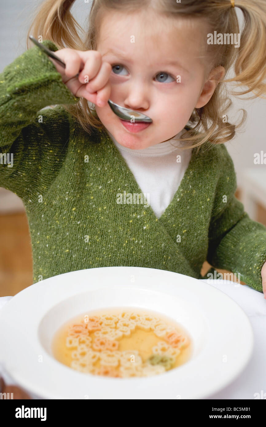 Small girl eating soup with teddy bear pasta Stock Photo - Alamy