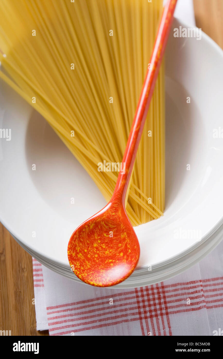 Spaghetti with cooking spoon on pile of plates Stock Photo - Alamy