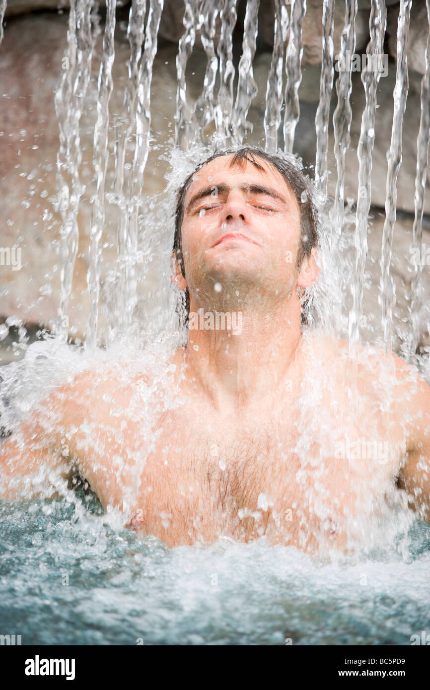 Young man standing under a waterfall Stock Photo - Alamy