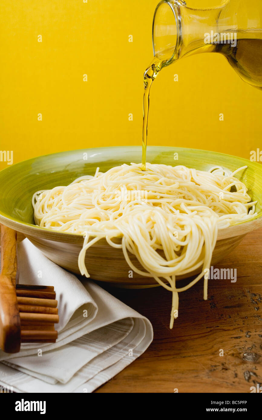 Pouring olive oil over cooked spaghetti Stock Photo - Alamy