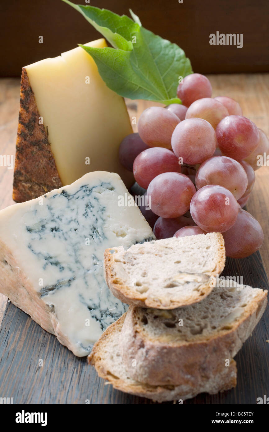 Pieces of Appenzeller and blue cheese, red grapes, bread Stock Photo ...