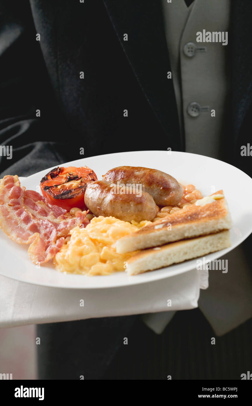 Butler serving English breakfast on plate Stock Photo - Alamy