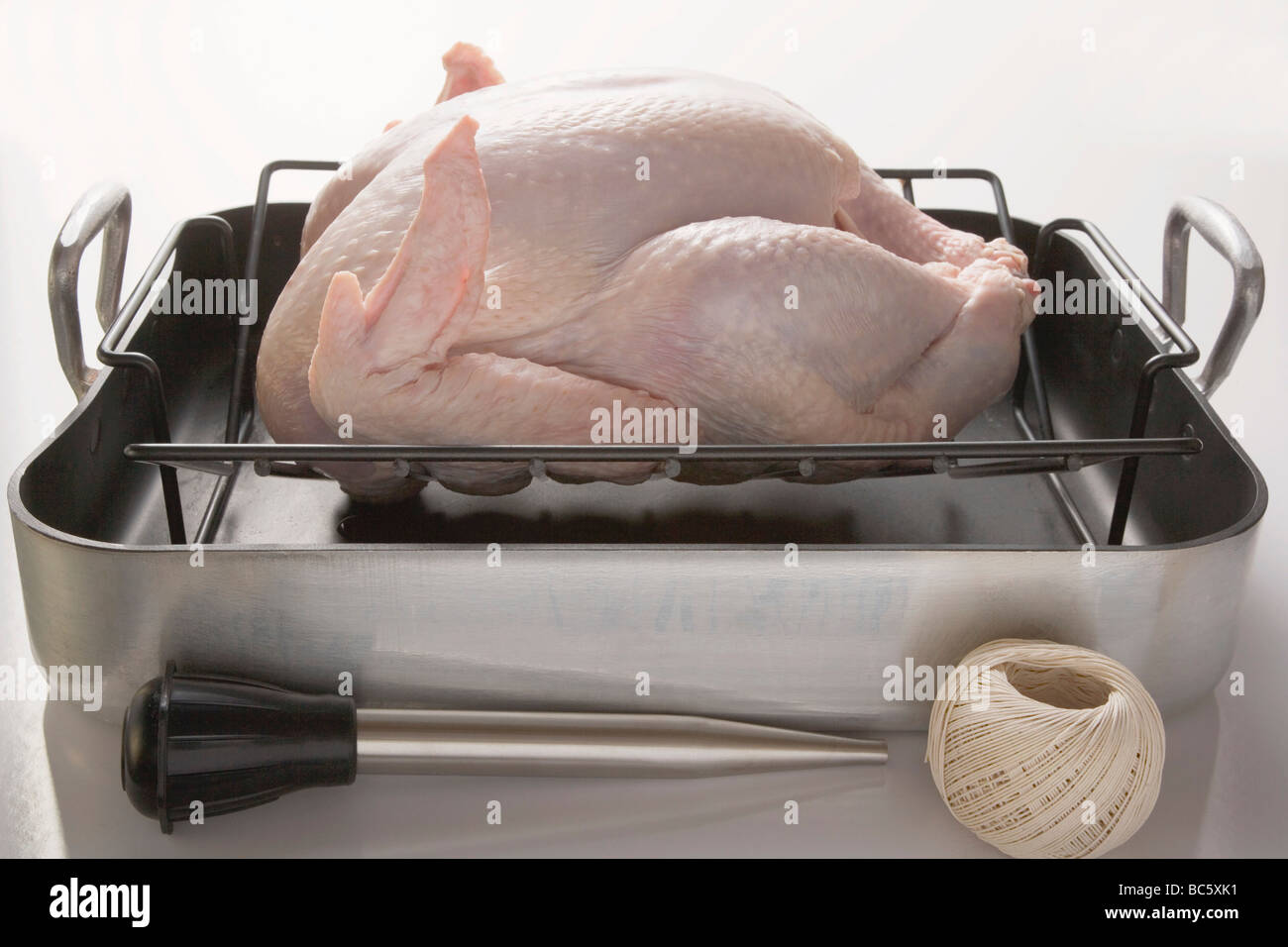 Chicken in roasting tin, kitchen utensils beside it Stock Photo - Alamy