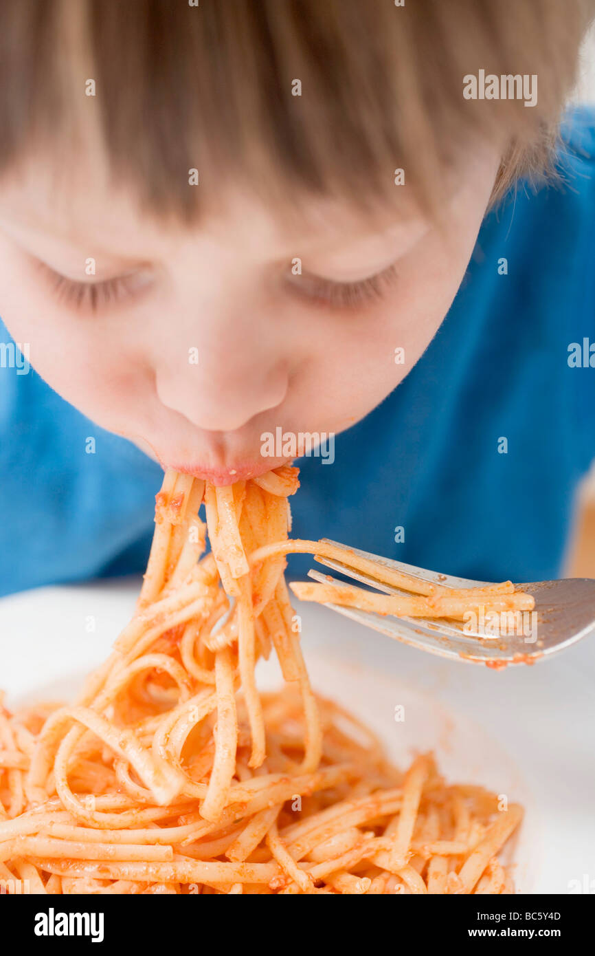 Small boy eating noodles with tomatoes Stock Photo - Alamy