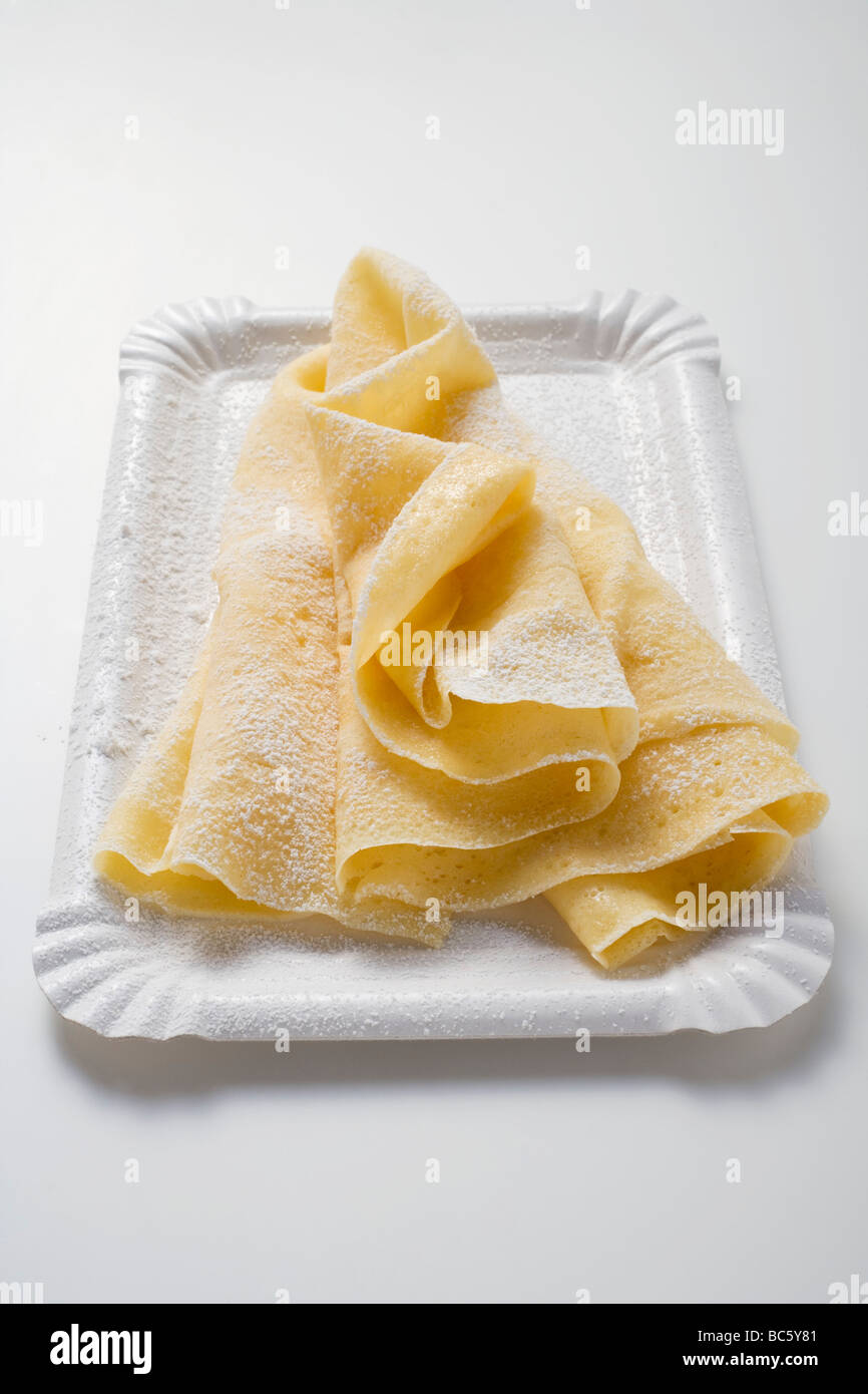 Wafer-thin crêpes with icing sugar on paper plate Stock Photo - Alamy
