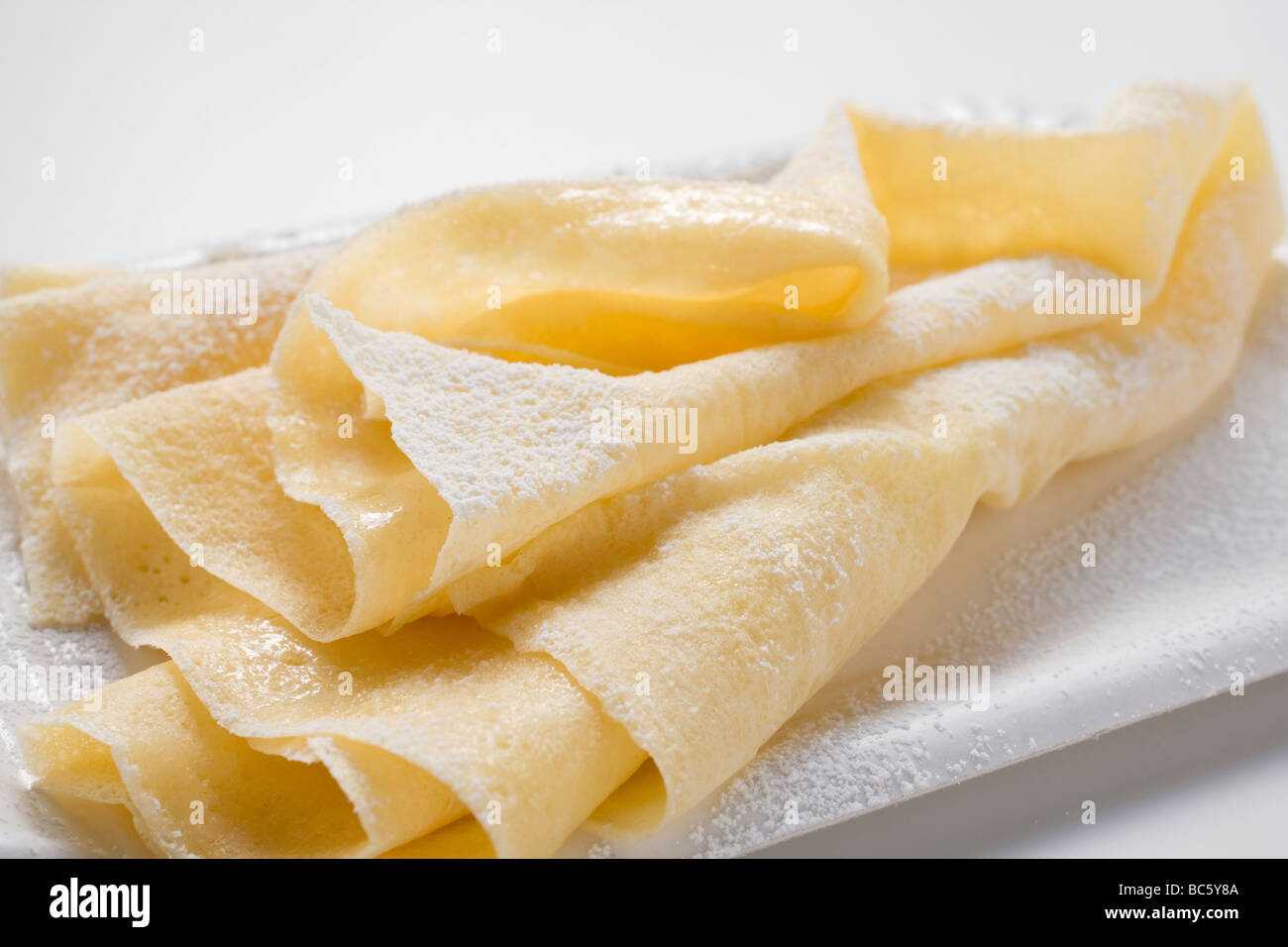 Wafer-thin crêpes with icing sugar on paper plate Stock Photo - Alamy