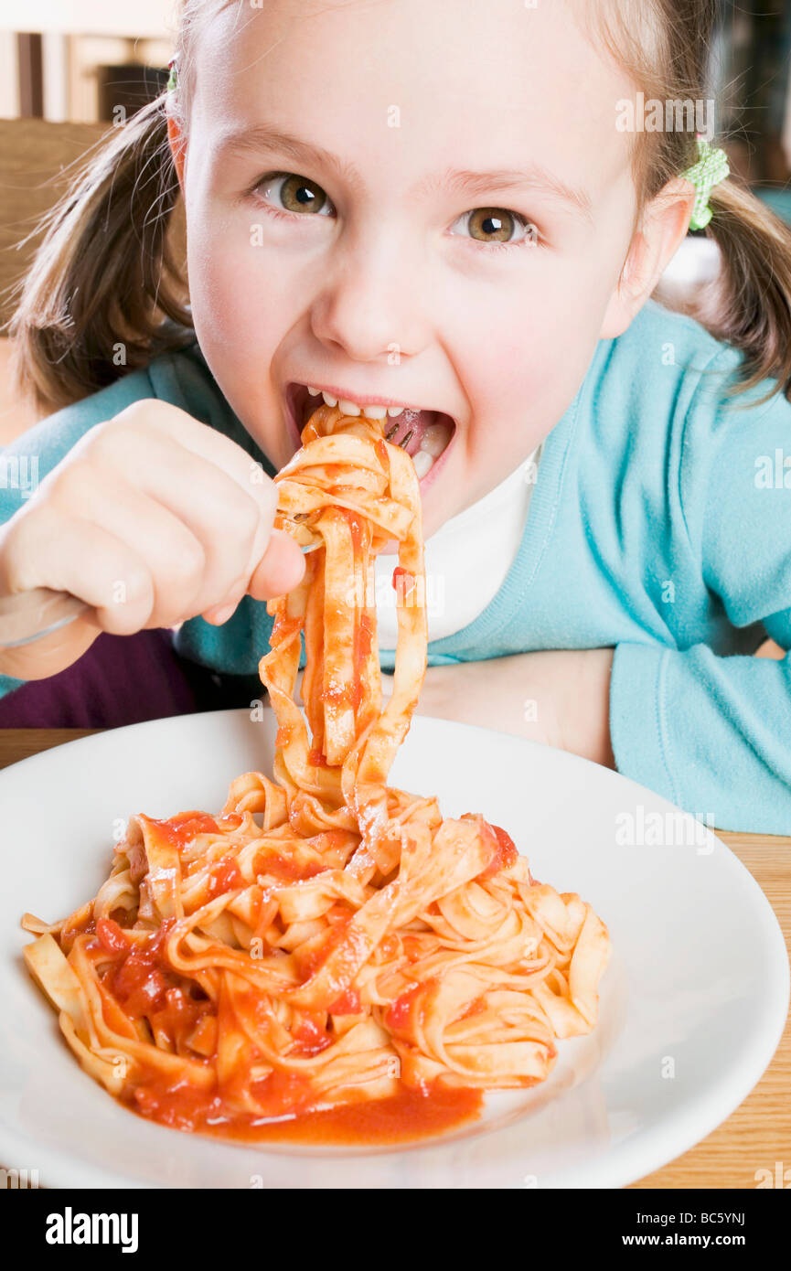 Girl eating ribbon pasta with tomato sauce Stock Photo - Alamy