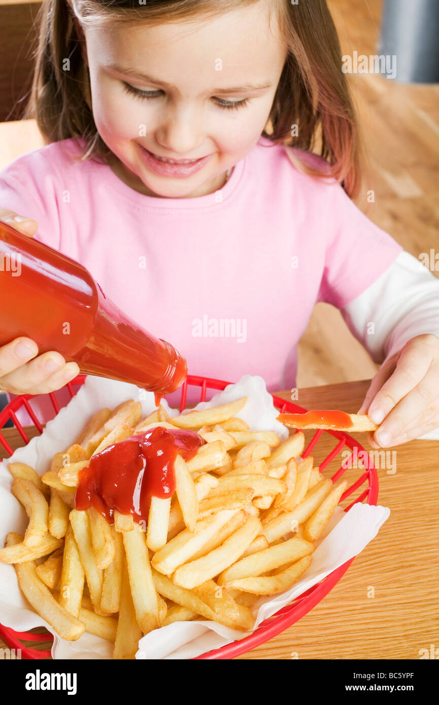 Girl putting ketchup on chips Stock Photo - Alamy