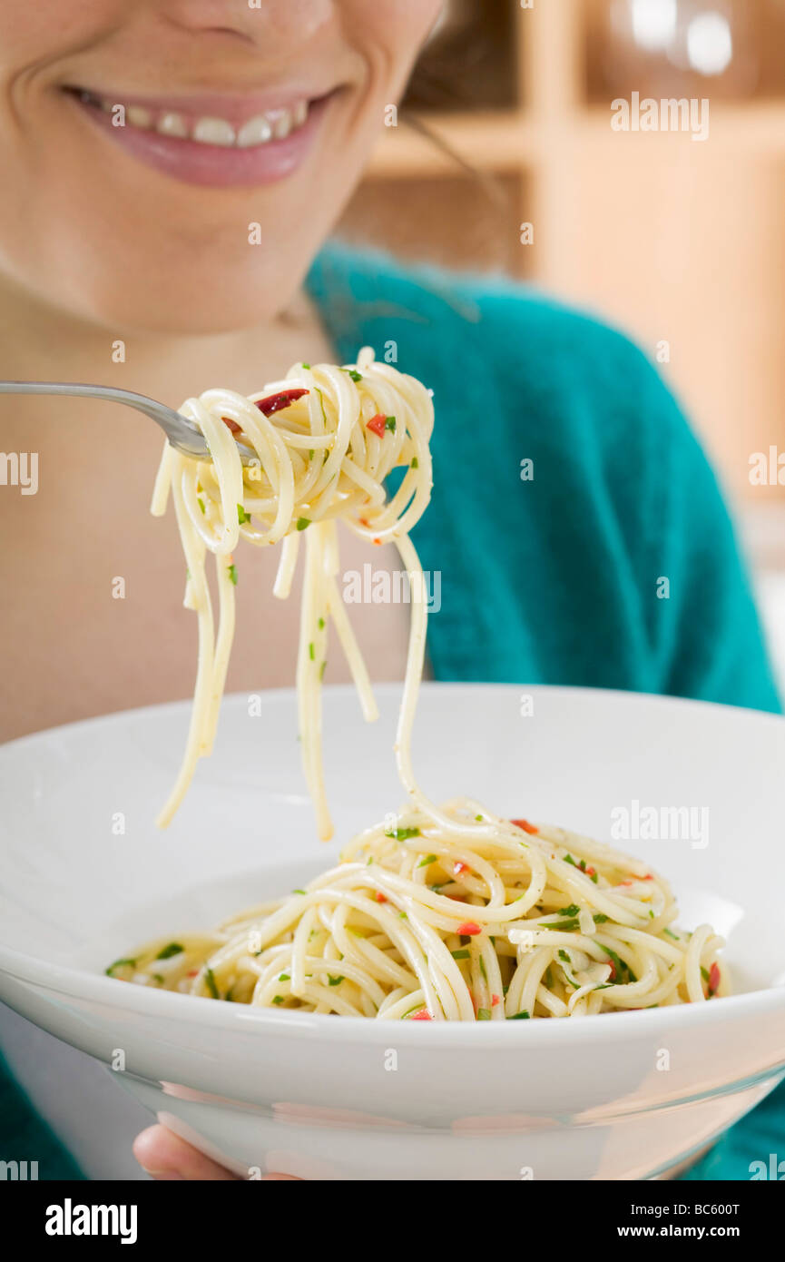 Young woman eating spaghetti with chillies Stock Photo - Alamy